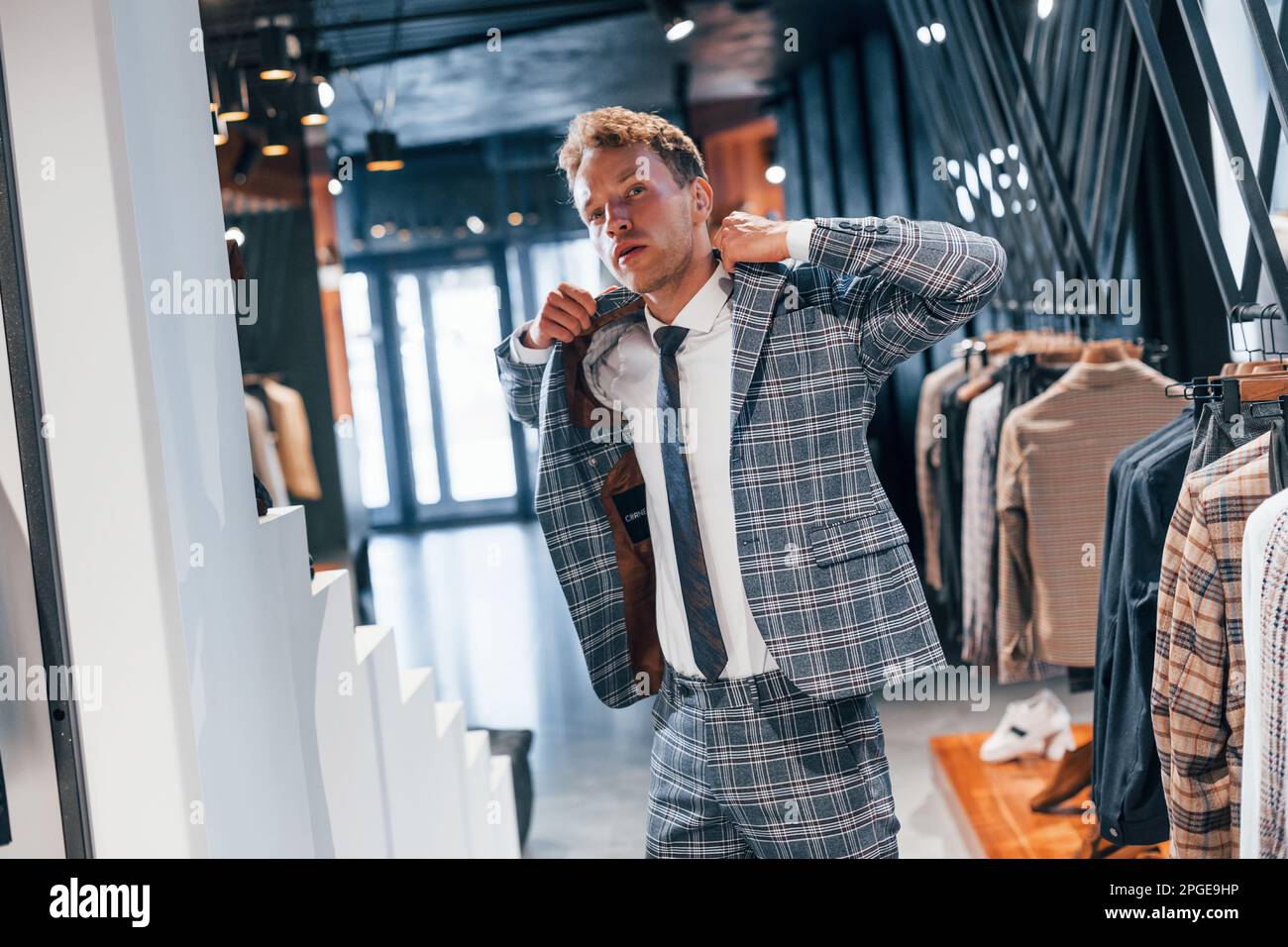 Tries on wear. Young guy in modern store with new clothes. Elegant ...