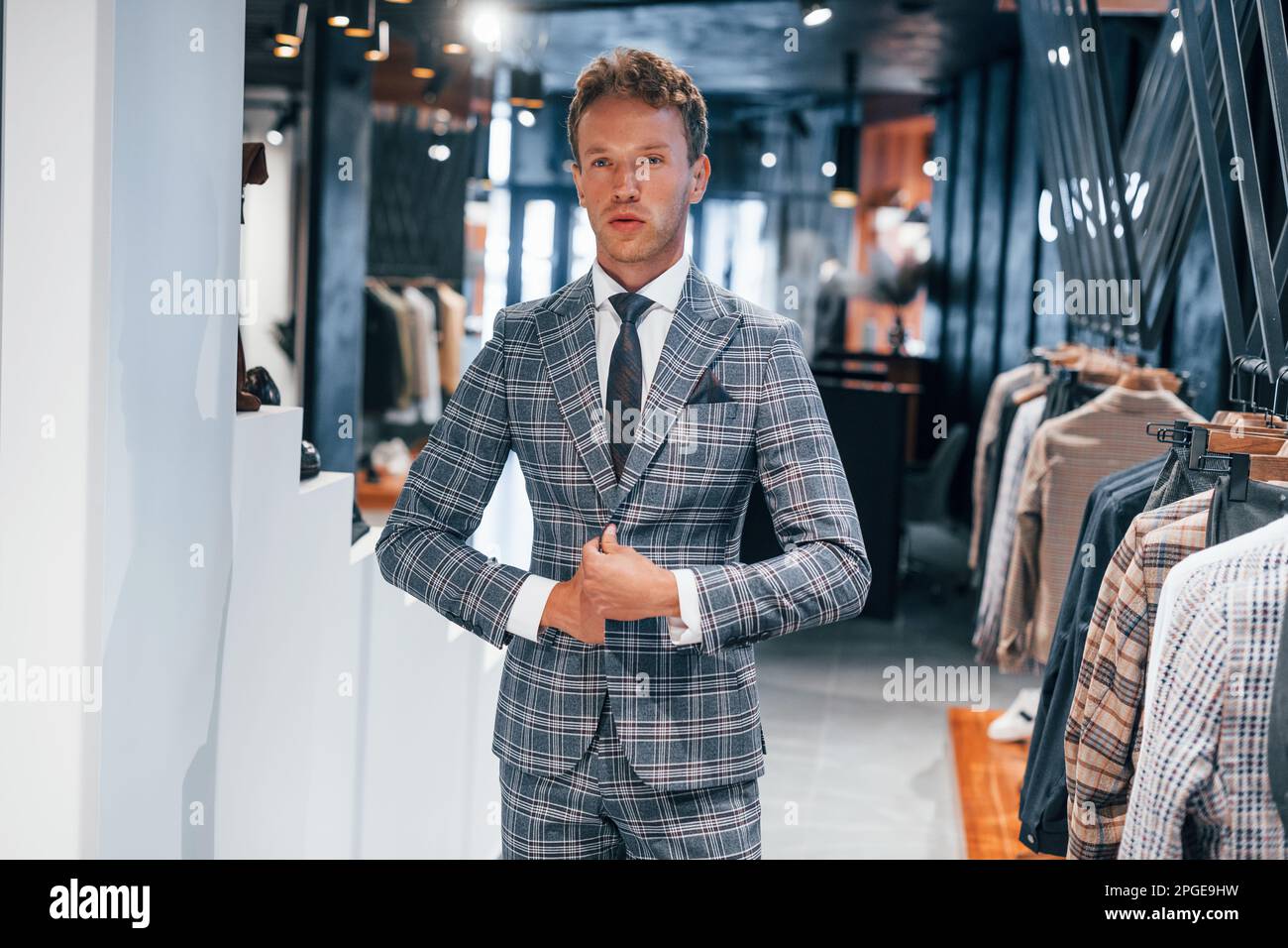 Tries on wear. Young guy in modern store with new clothes. Elegant ...