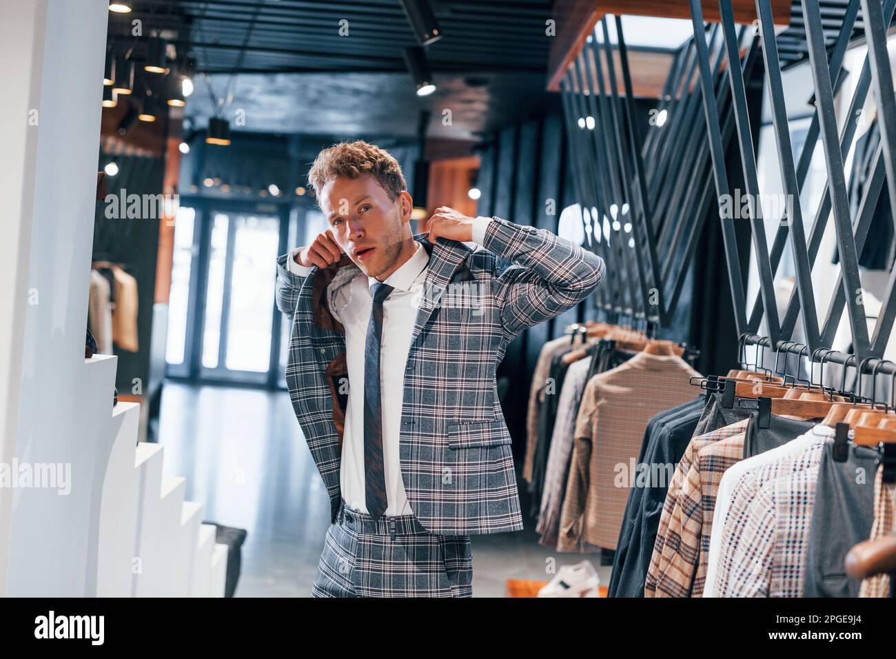 Tries on wear. Young guy in modern store with new clothes. Elegant ...