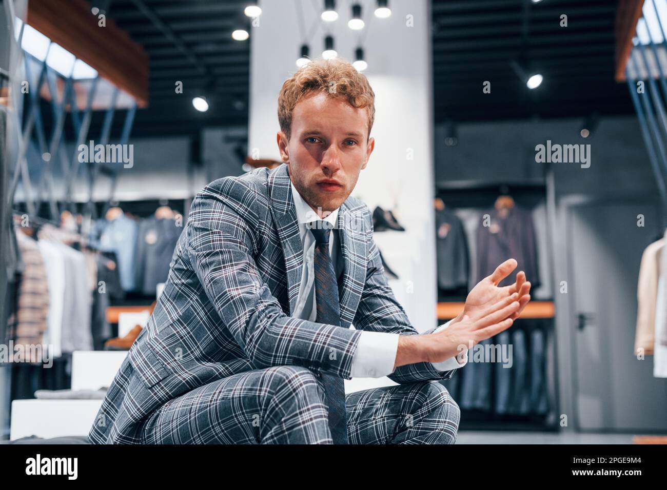 Young guy in modern store with new clothes. Elegant expensive wear for ...