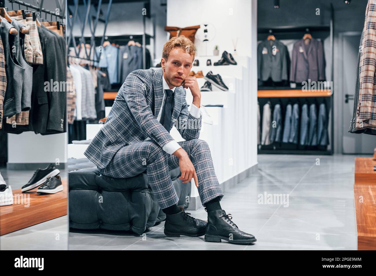 Young guy in modern store with new clothes. Elegant expensive wear for ...