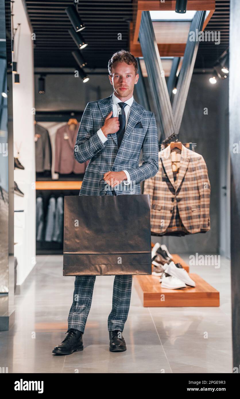 Holds bag with purchase. Young guy in modern store with new clothes ...