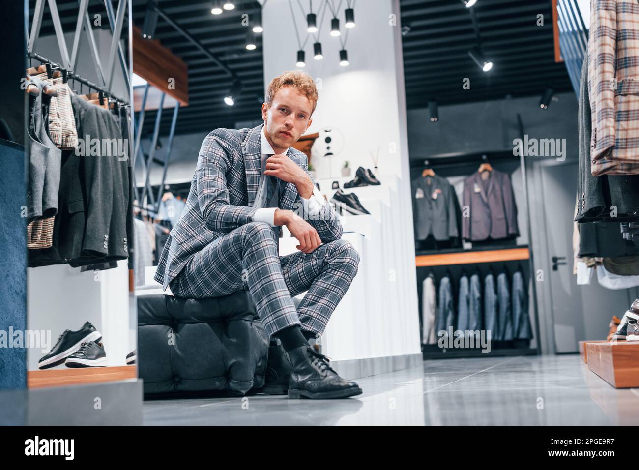 Young guy in modern store with new clothes. Elegant expensive wear for ...