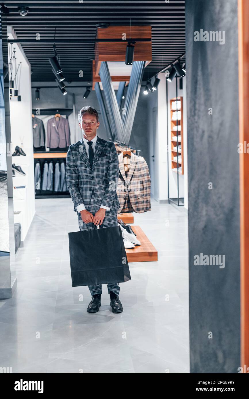 Young guy in modern store with new clothes. Elegant expensive wear for ...