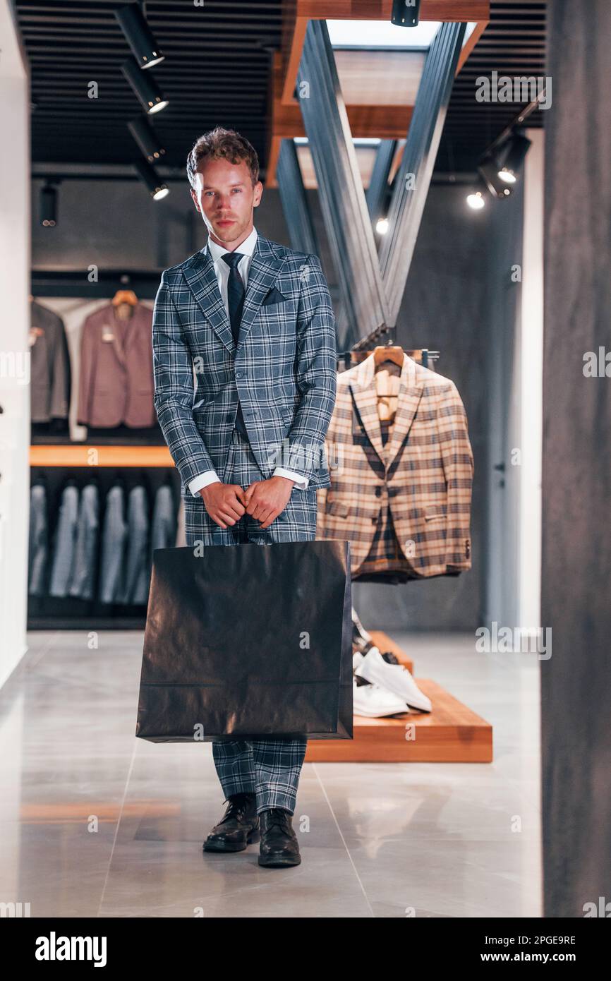 Young guy in modern store with new clothes. Elegant expensive wear for ...