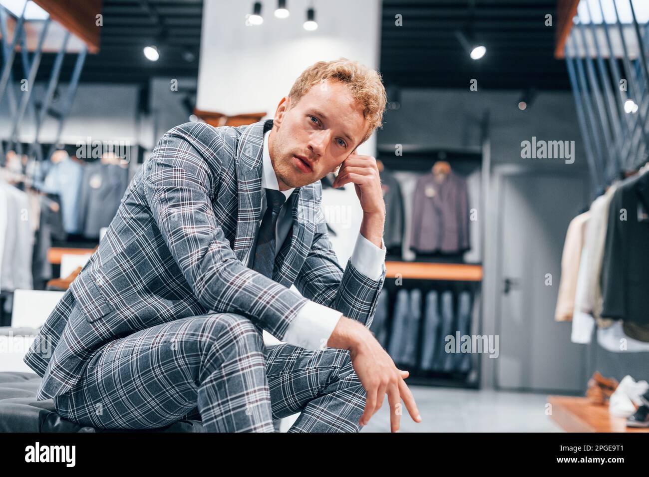 Young guy in modern store with new clothes. Elegant expensive wear for ...