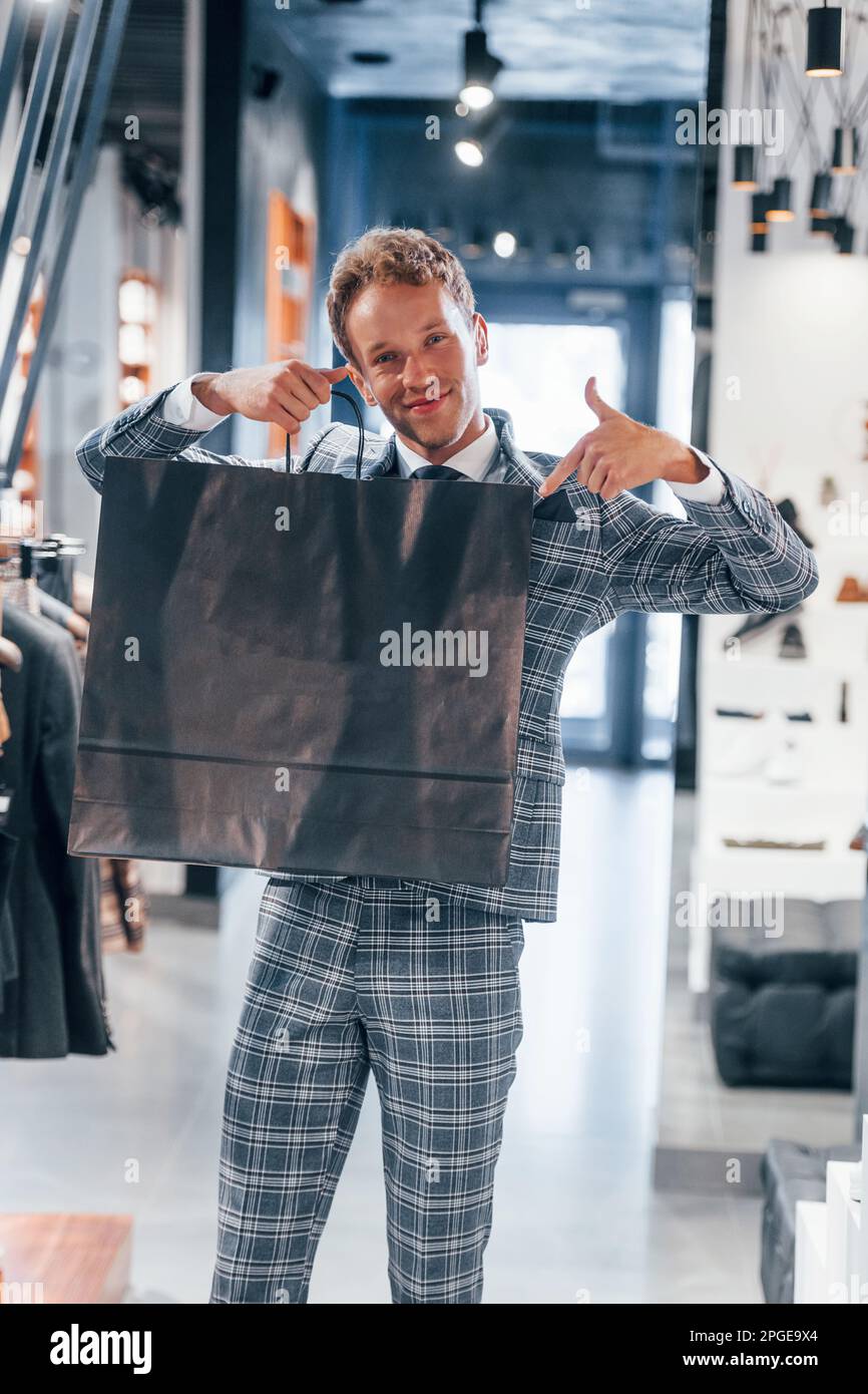 Holds bag with purchase. Young guy in modern store with new clothes ...