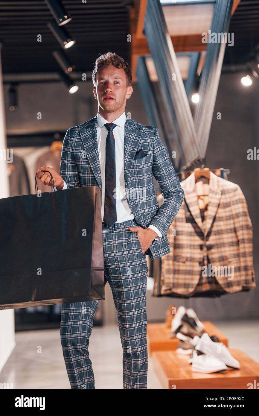 Holds bag with purchase. Young guy in modern store with new clothes ...