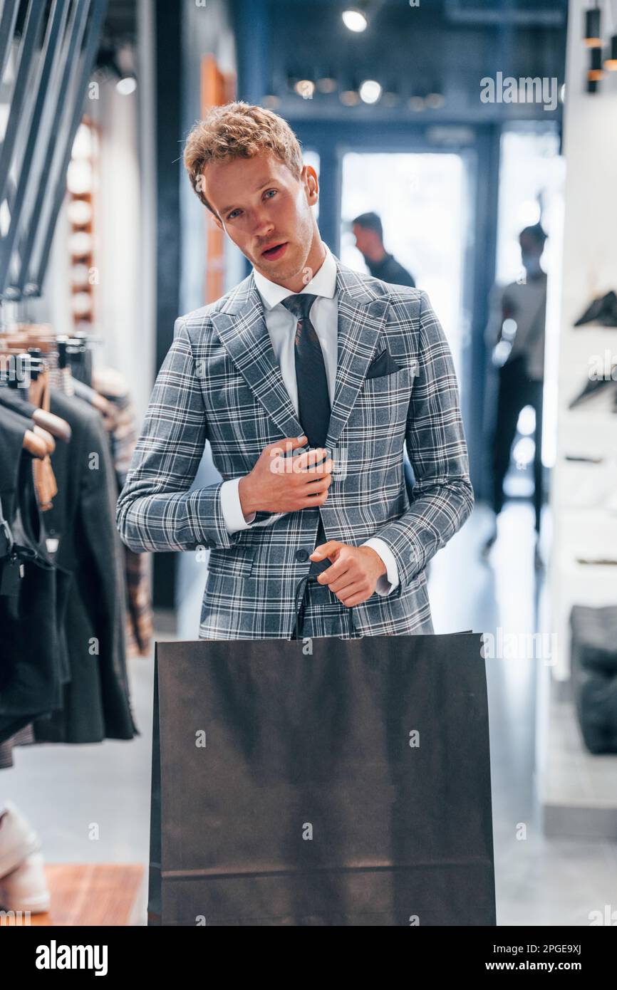Holds bag with purchase. Young guy in modern store with new clothes ...