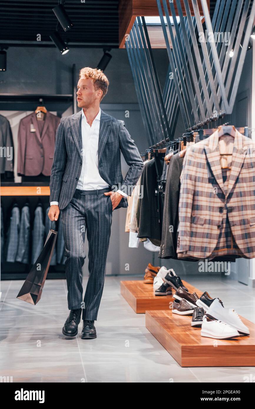 Shopping day. Young guy in modern store with new clothes. Elegant ...
