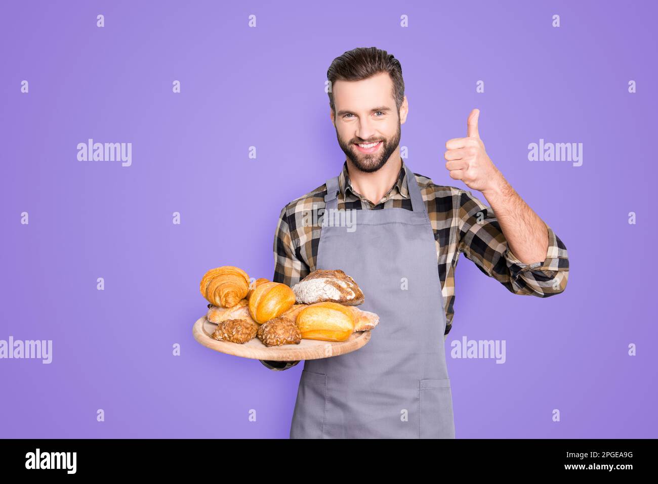 Portrait of positive attractive baker in uniform with stubble holding ...