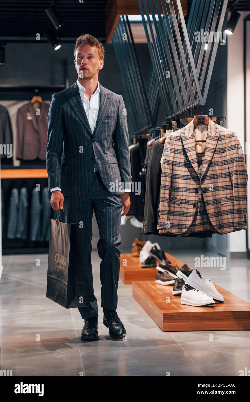 Walks with bag in hand. Young guy in modern store with new clothes ...