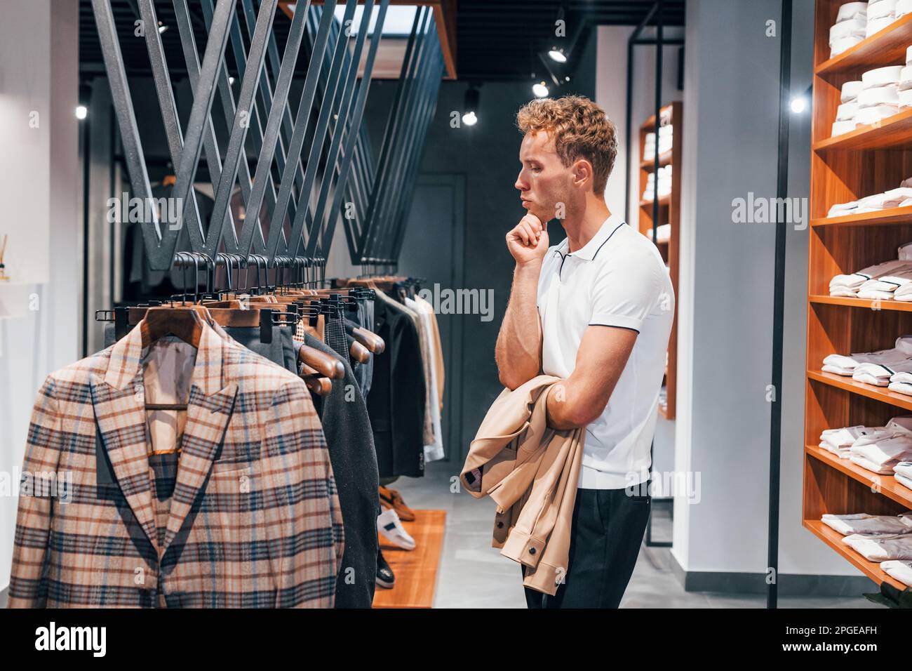 Tries on wear. Young guy in modern store with new clothes. Elegant ...