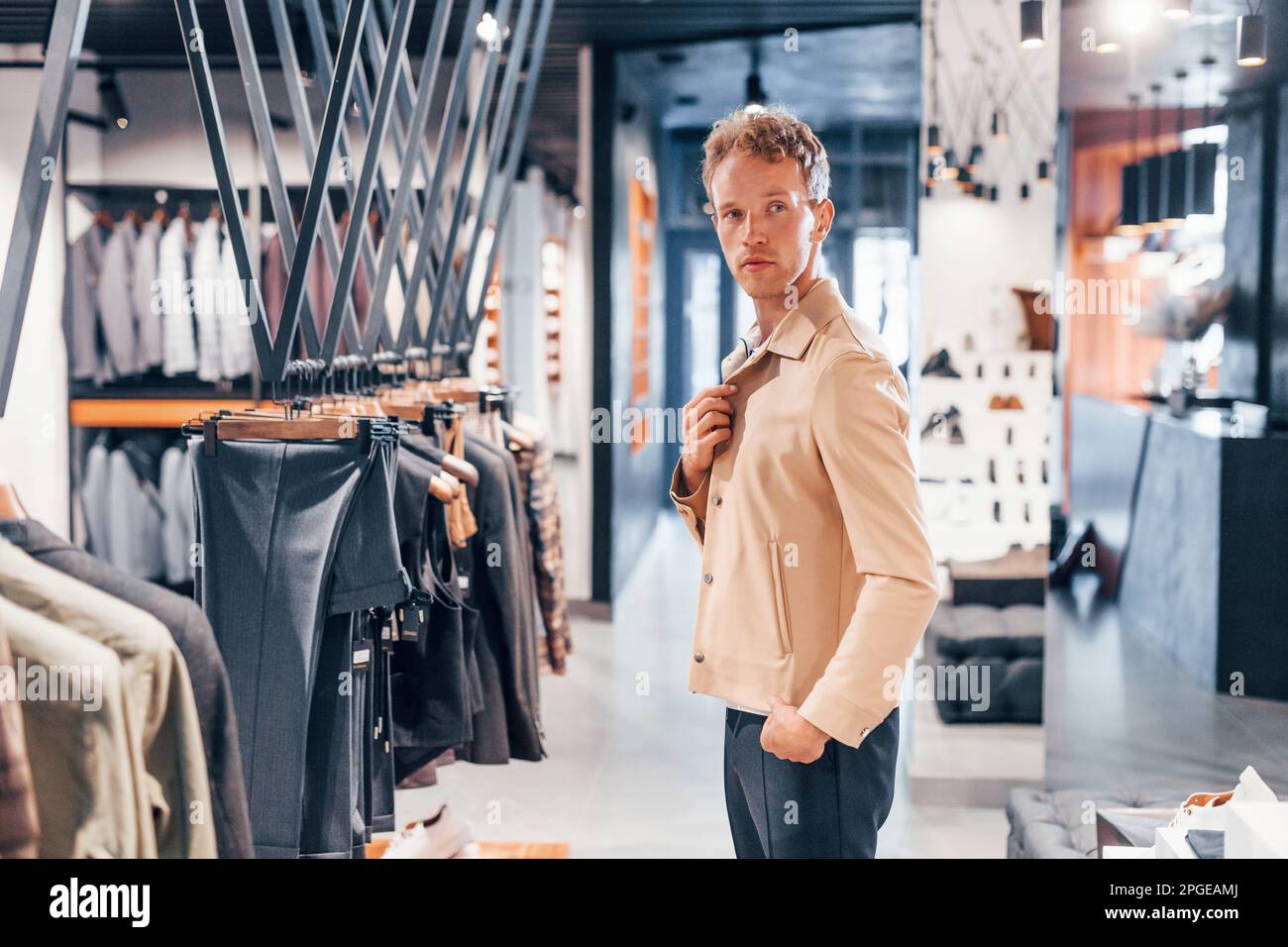 Quality products. Young guy in modern store with new clothes. Elegant ...