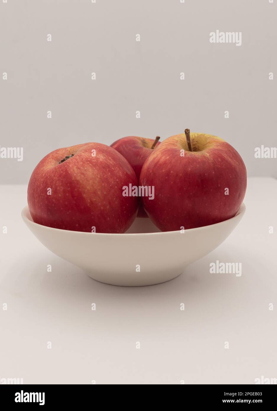Three small red apples in a white cup. Vertical and close-up Stock ...