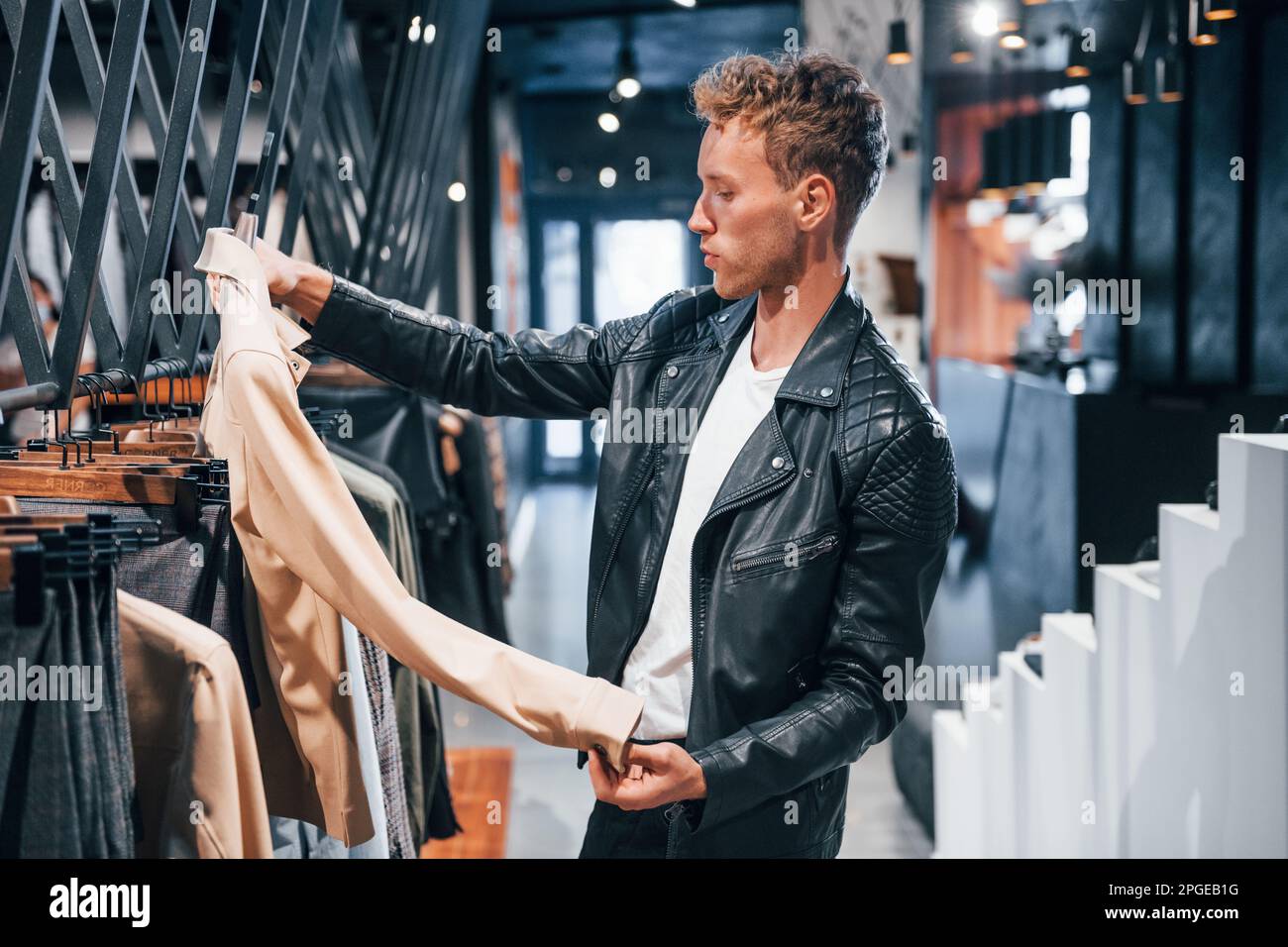 Quality products. Young guy in modern store with new clothes. Elegant ...