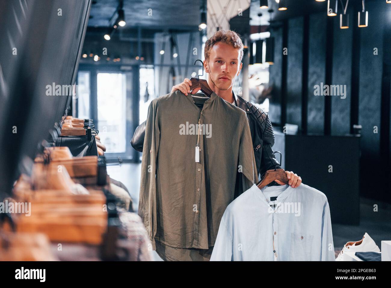 Quality products. Young guy in modern store with new clothes. Elegant ...