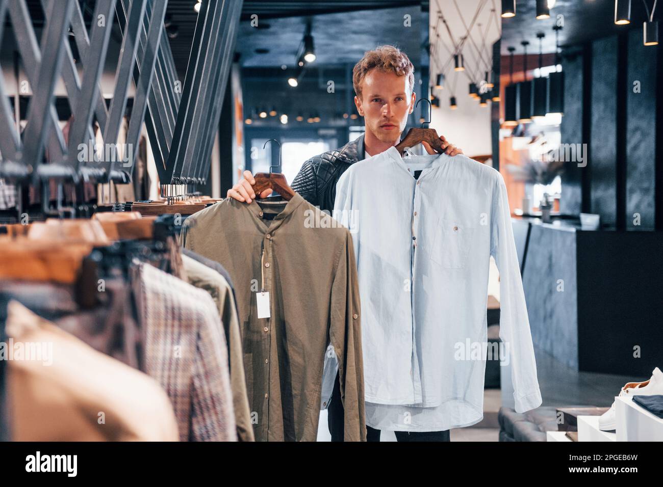 Quality products. Young guy in modern store with new clothes. Elegant ...
