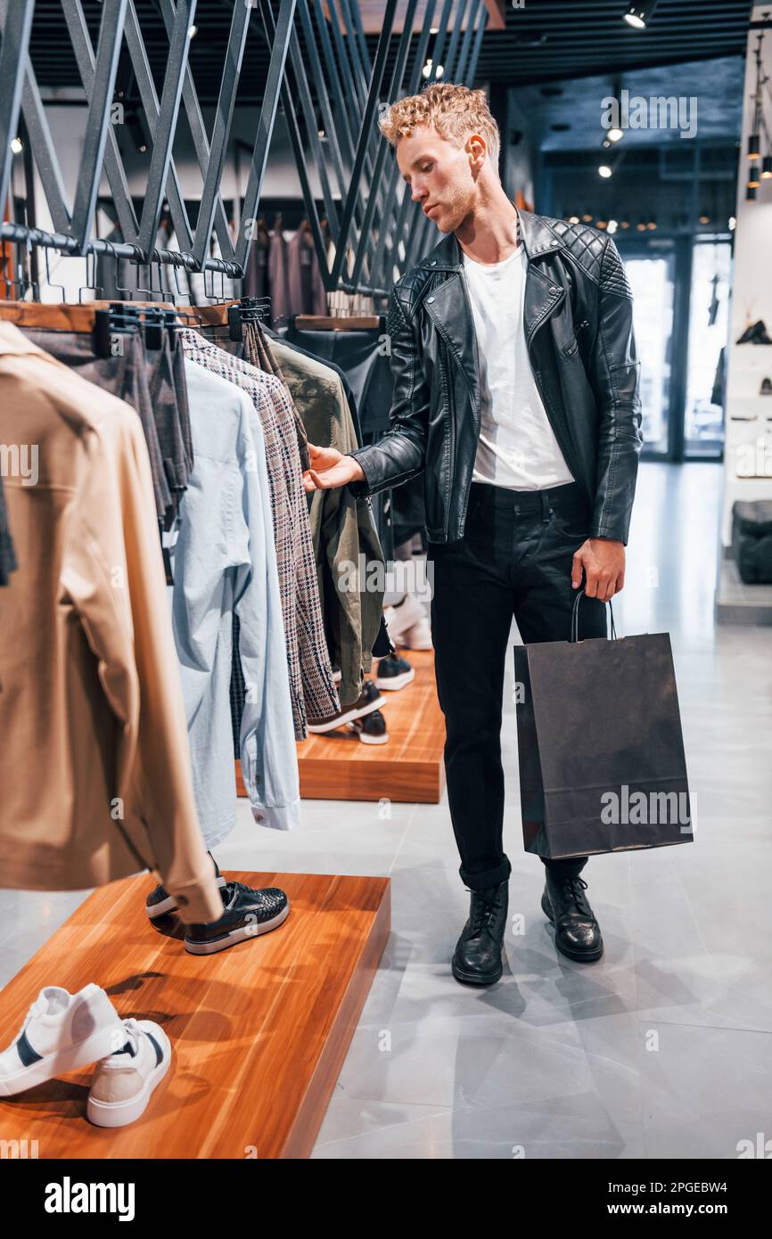 Weekend shopping. Young guy in modern store with new clothes. Elegant ...