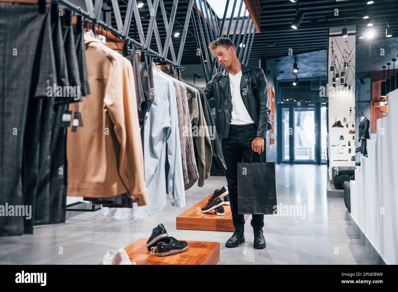 Big choice. Young guy in modern store with new clothes. Elegant ...