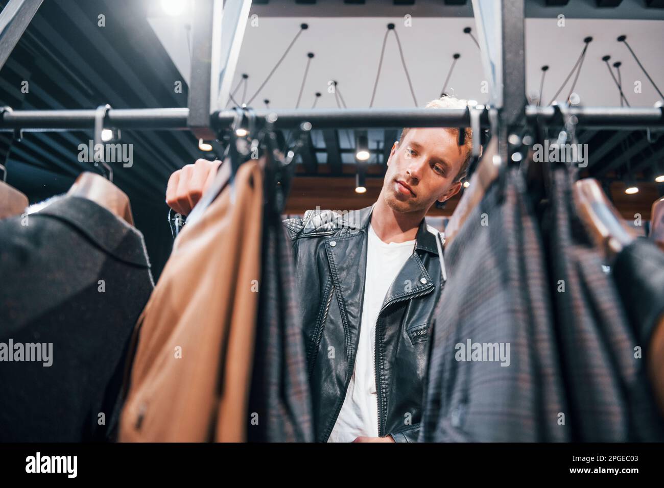 Weekend shopping. Young guy in modern store with new clothes. Elegant ...