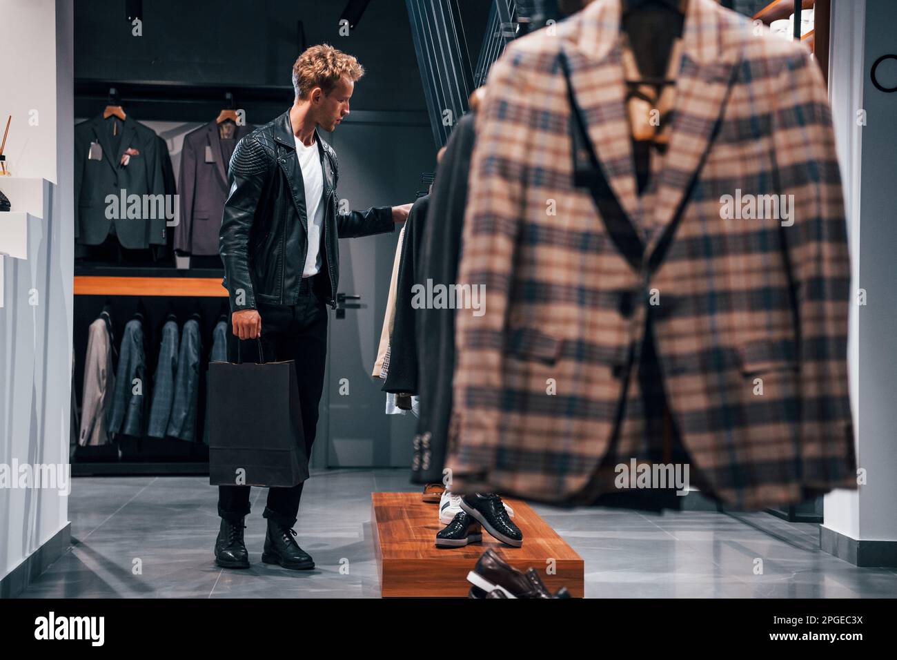 Weekend shopping. Young guy in modern store with new clothes. Elegant ...