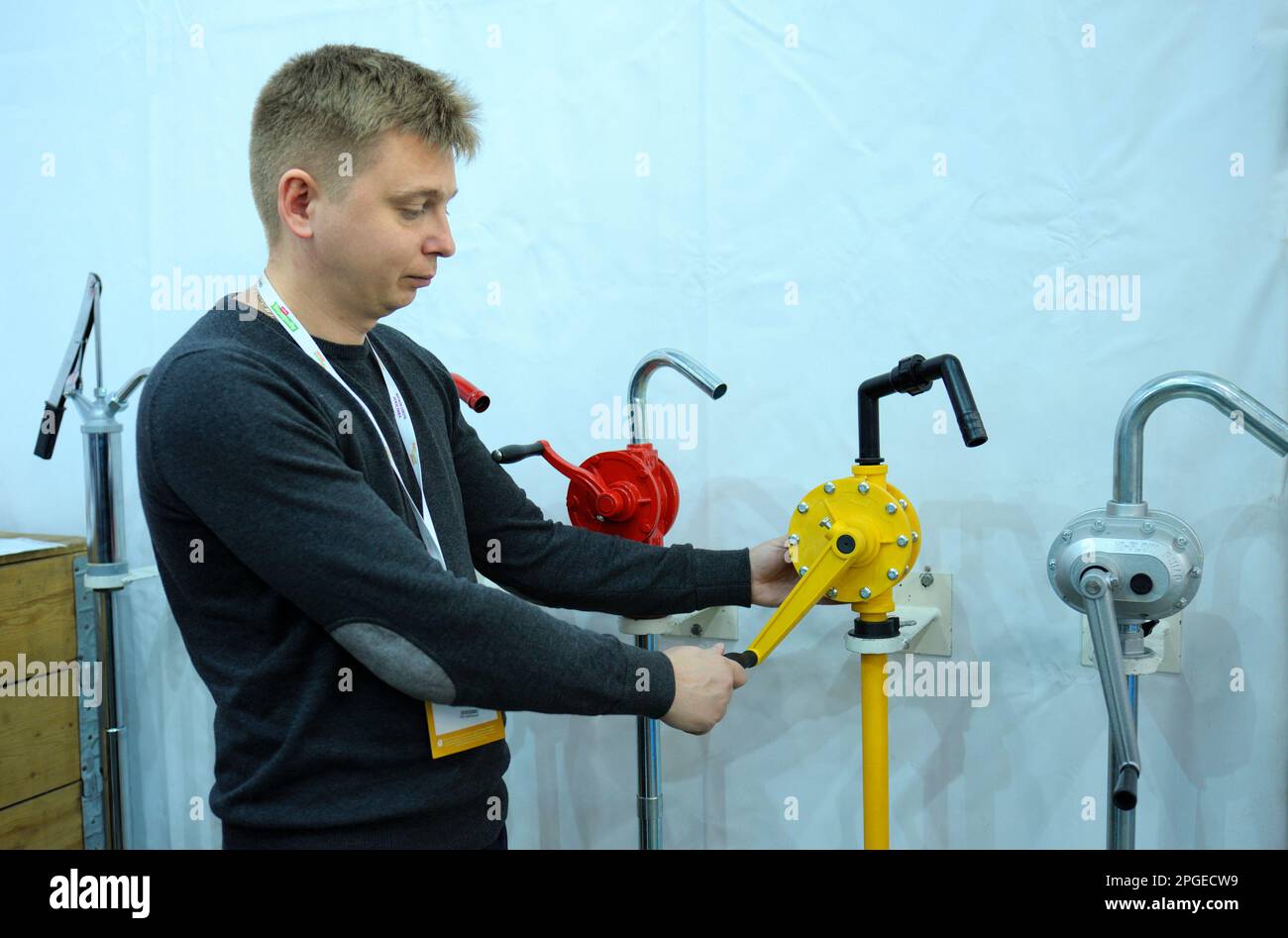 Man sales manager shows Rotary hand pumps placed on stand. Exhibition ...