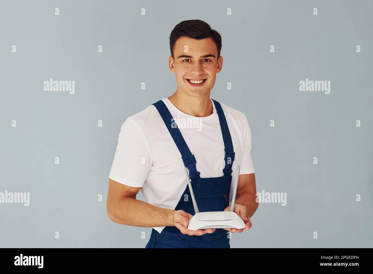 Holds wifi router. Male worker in blue uniform standing inside of ...