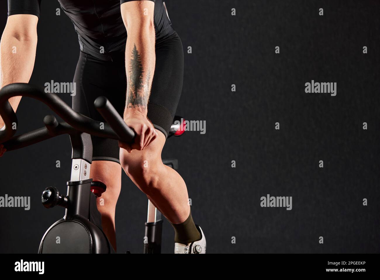 Close-up of the legs and arms of a cyclist during a workout in the gym ...