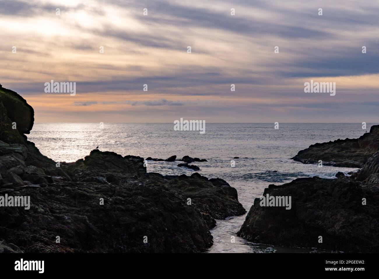 The cloudy sunset sky over the sea captured from the rocky coast in ...