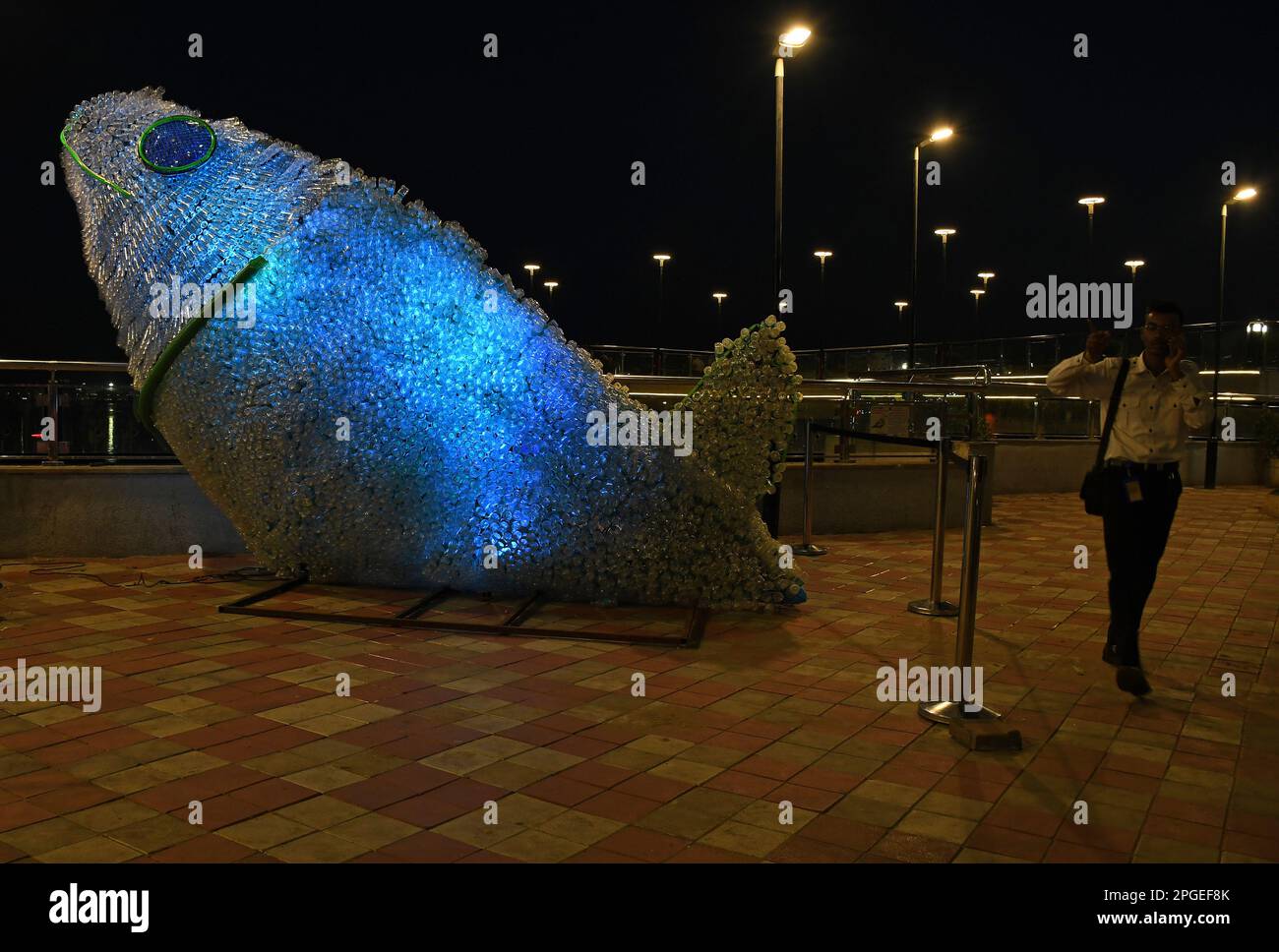 A man walks near a lit PET (Polyethylene terephthalate) bottle fish ...