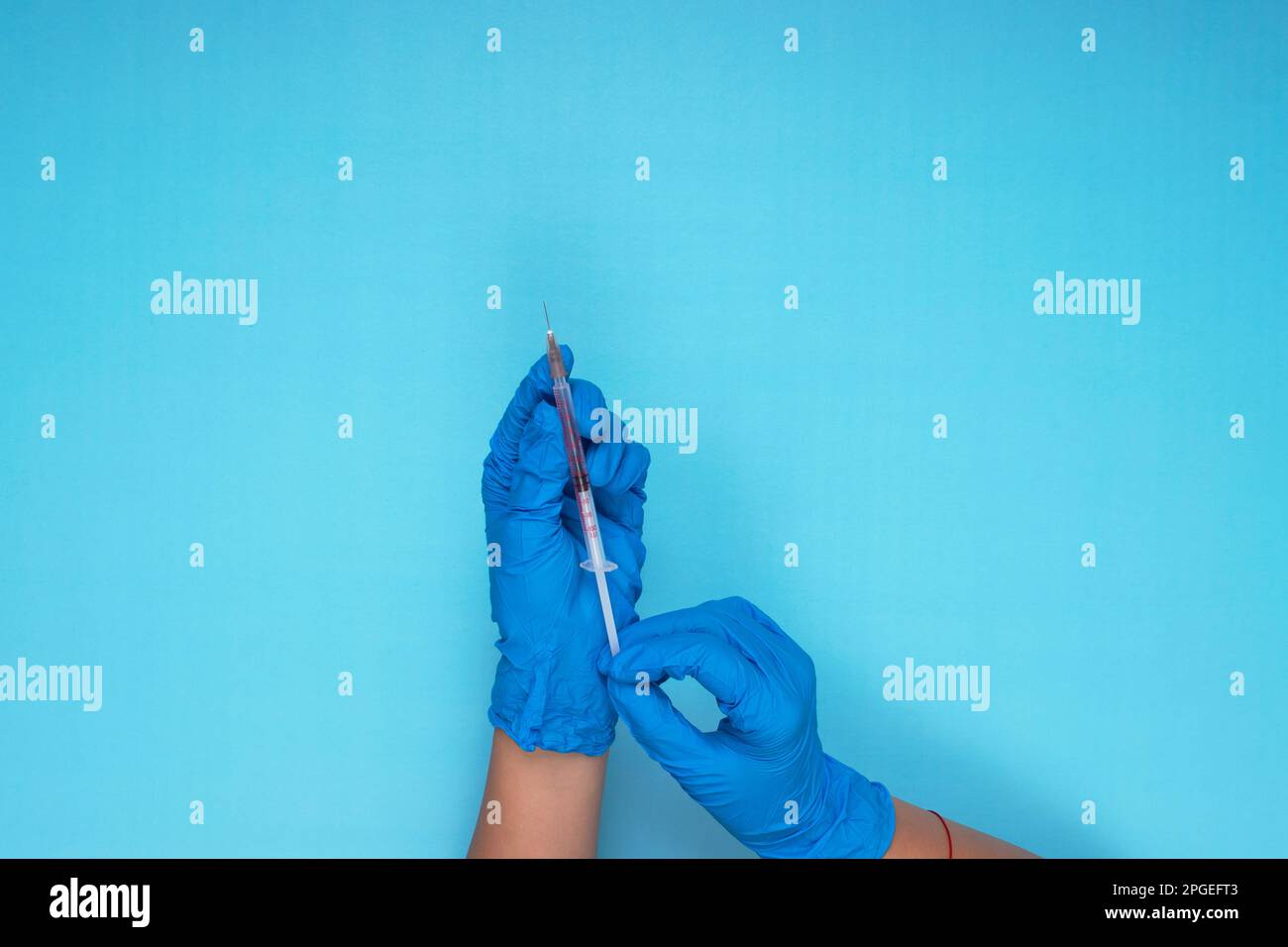 hand held needle with blue glove on light blue background Stock Photo ...