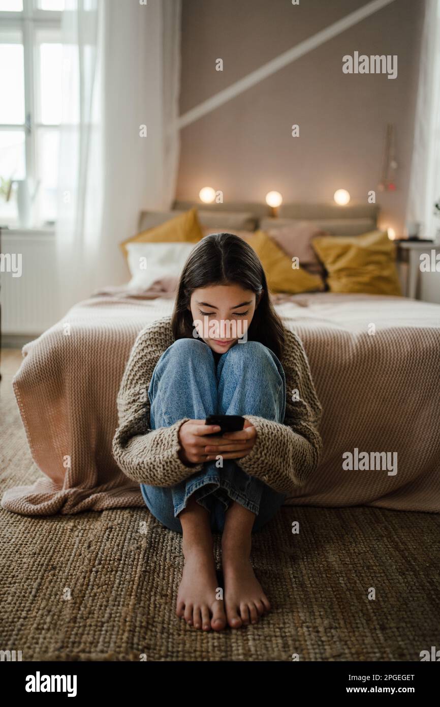 Teenage girl sitting on the floor and scrolling her smartphone Stock Photo - Alamy