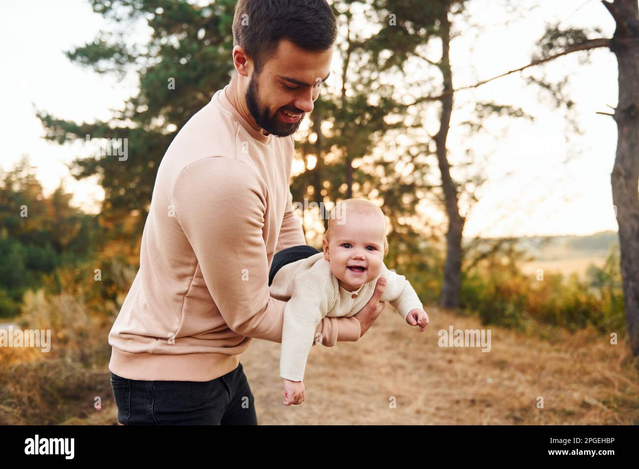 Bearded father playing with his child outdoors at sunny daytime ...