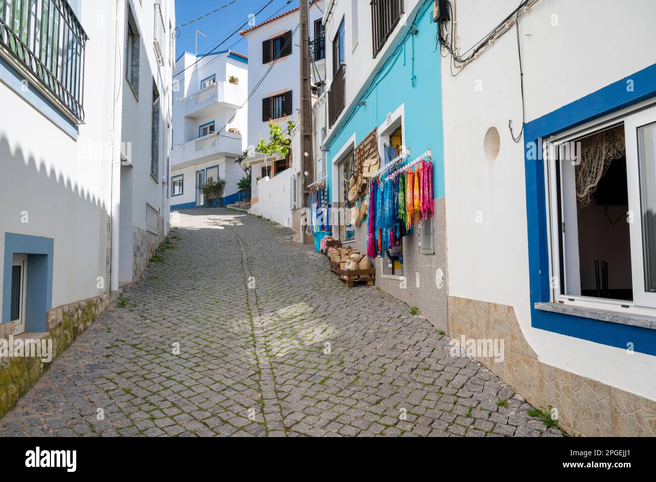 A cobbled street in Praia de Luz, Algarve Portugal showing shops and ...