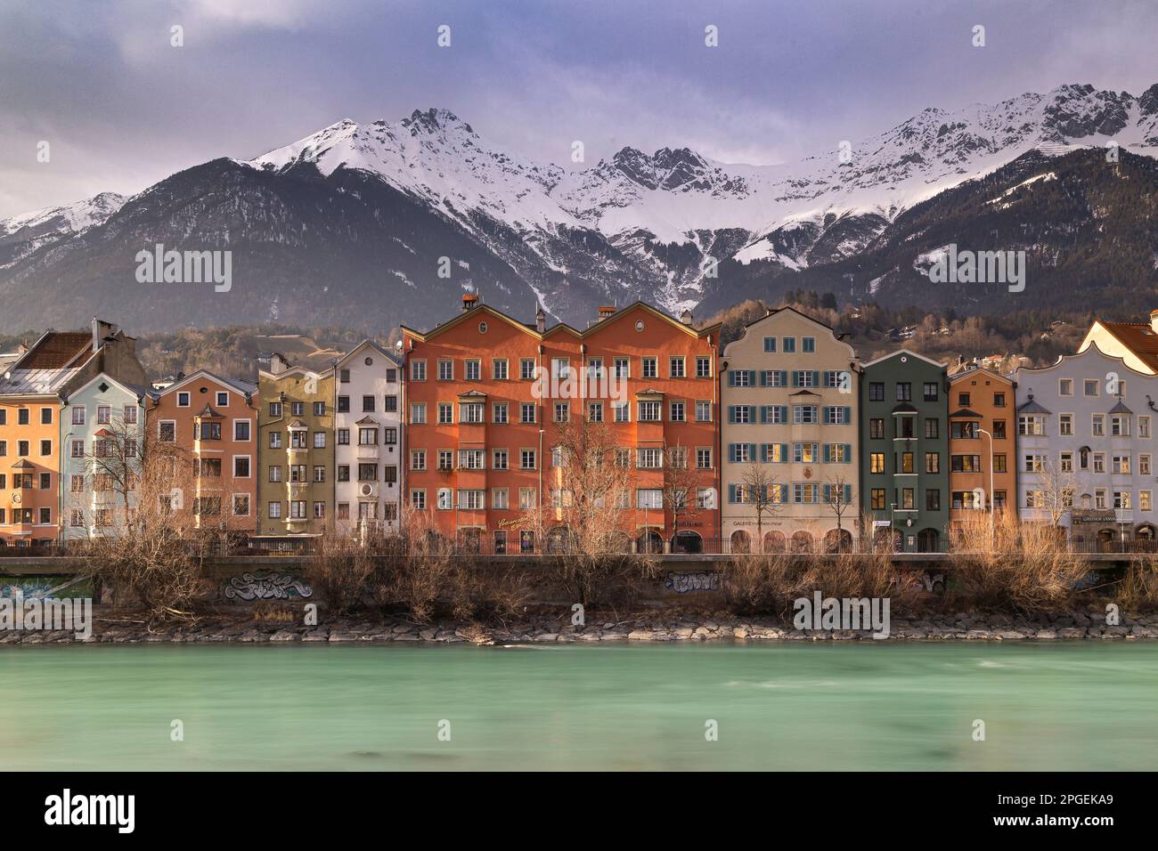 Colorful houses along the Inn river with snow-covered mountains in the ...