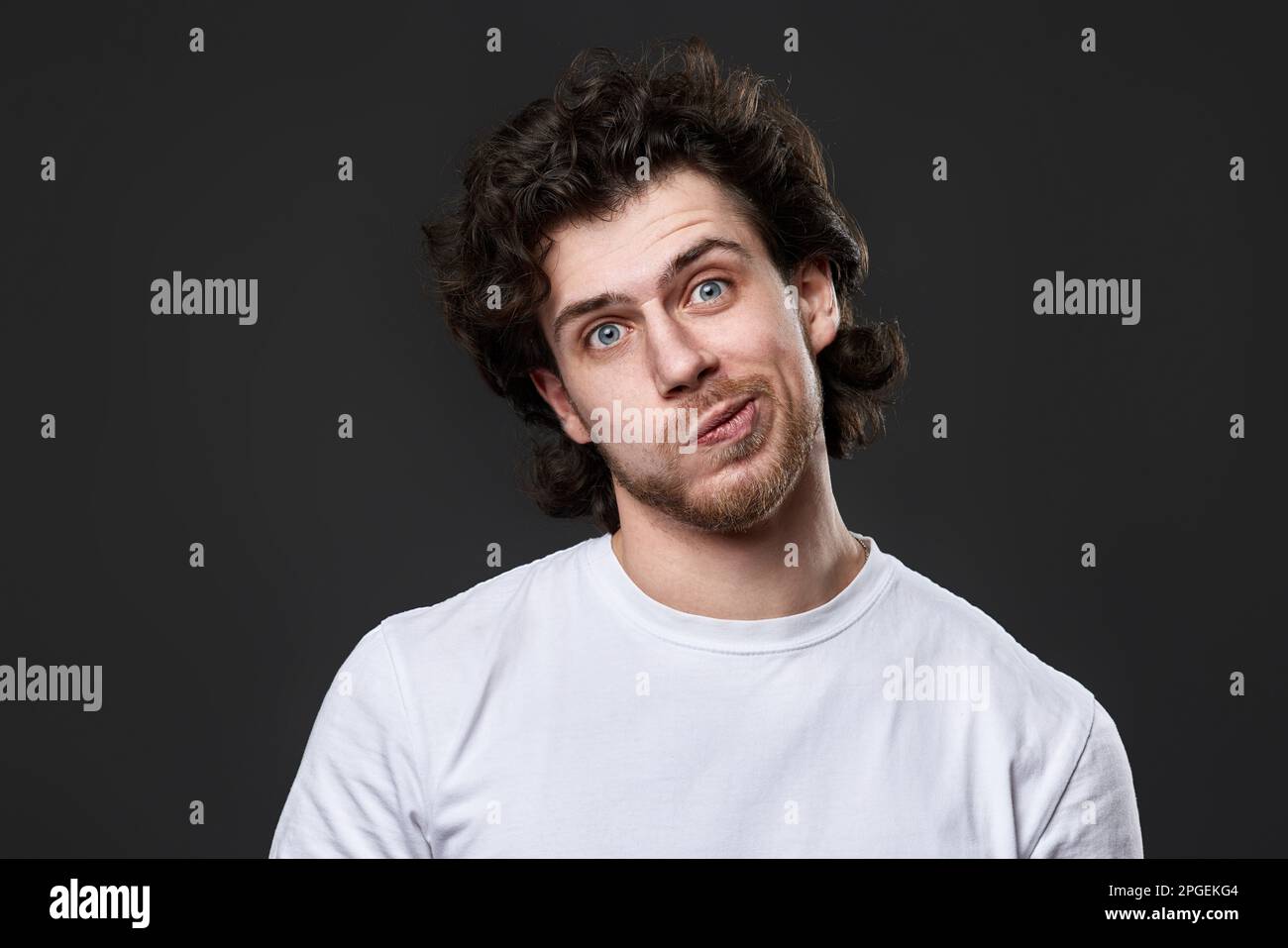 skeptic and nervous man in white t-shirt on dark gray background Stock ...