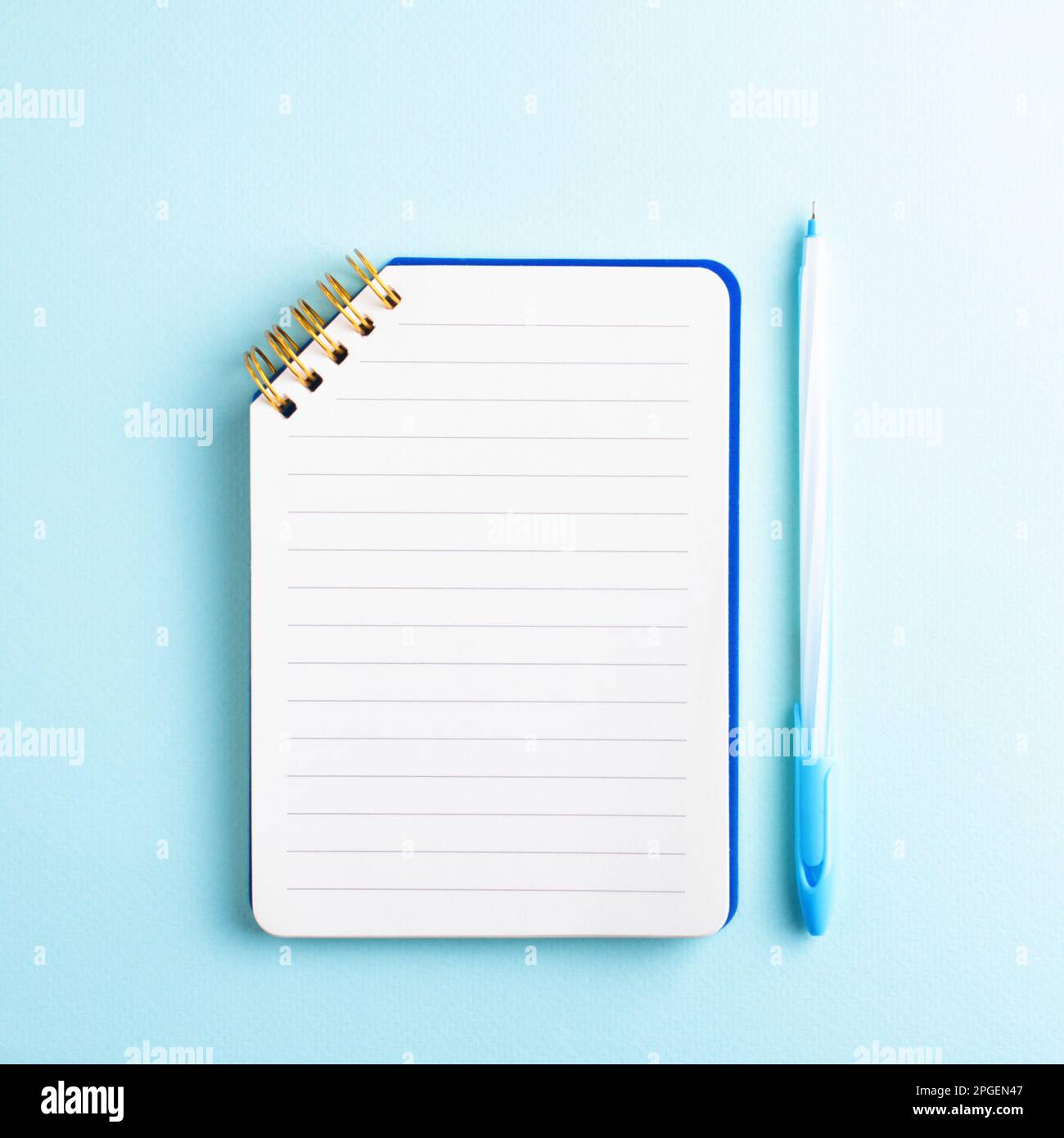 Open notebook with blank page and blue pen on blue background. Minimal ...