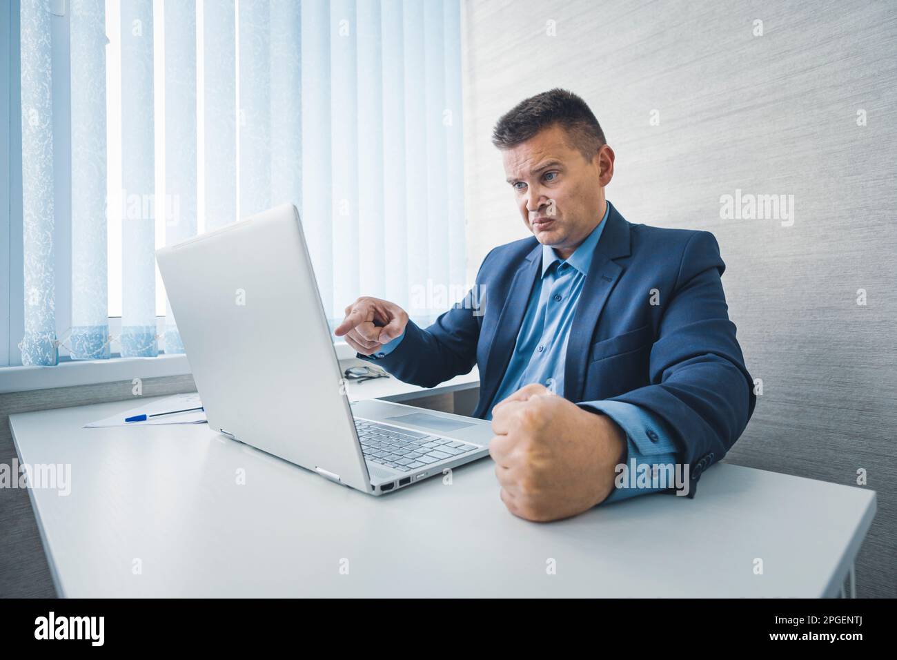 angry businessman in a jacket slams his fist on the table in anger. the ...