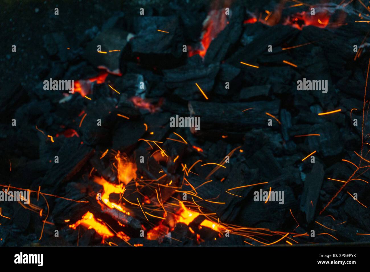 Coals with sparks in a huge old metal grill background Stock Photo - Alamy