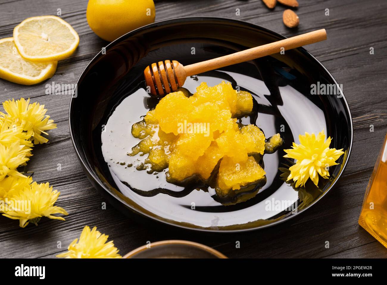 Crystallized honey, dipper in a black plate on a dark wooden background ...