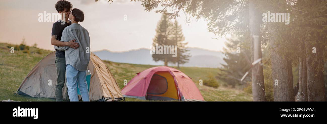 Young couple in love kissing at tents in camping site in mountains ...