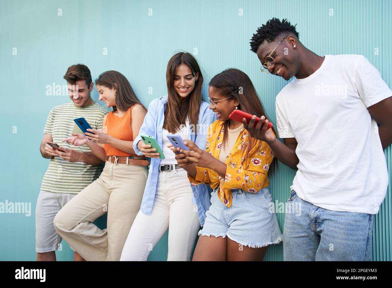 Young smiling multicultural group of friends using cell phones ...