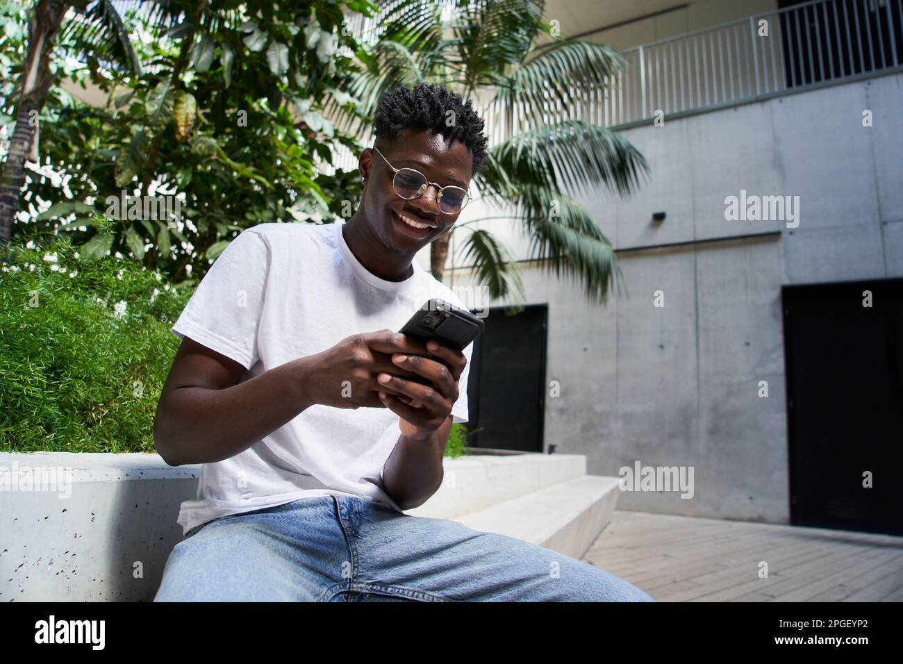 Portrait smiling black boy using cell phone college campus. Cheerful ...
