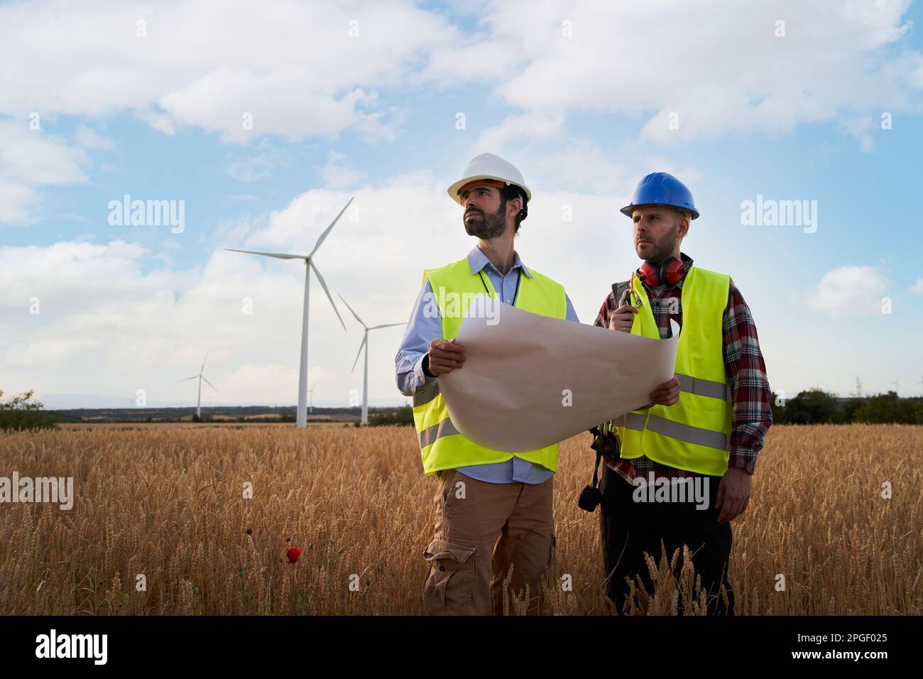 Two engineers in hard hats work holding plane in agricultural field ...