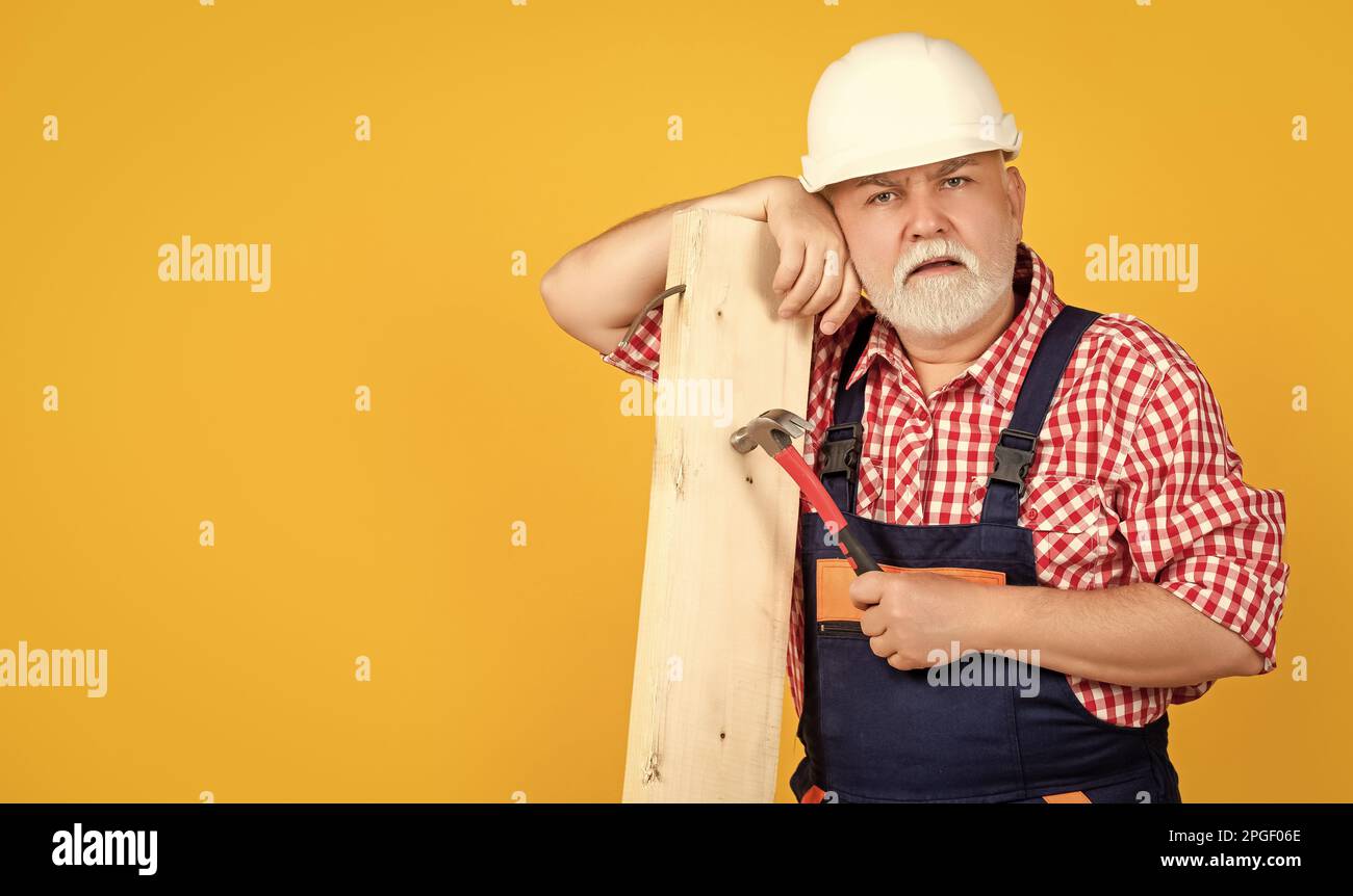 tired old man woodworker in helmet on yellow background Stock Photo - Alamy