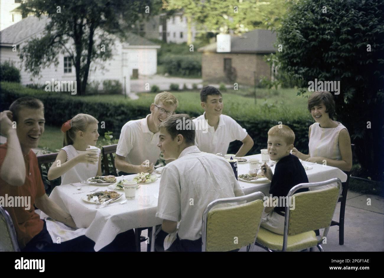 1963, historical, family meal, a group of children sitting outside at a ...