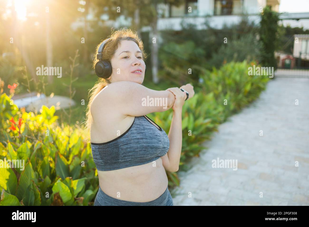 Adorable fat woman in tracksuit is engaged in fitness outdoor side view ...