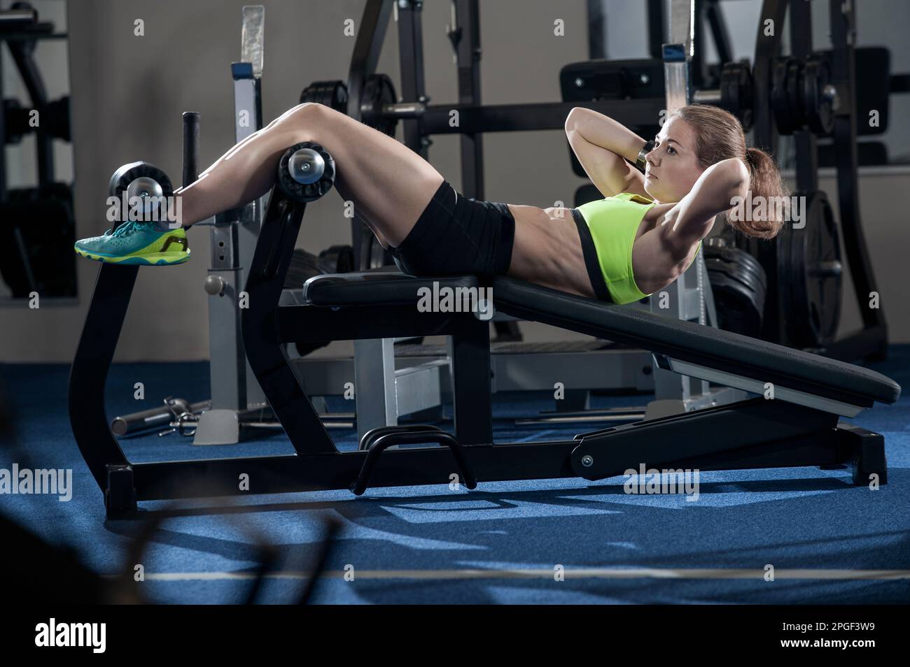 Mid adult woman going sit-ups on bench for trains her abdominal muscles ...