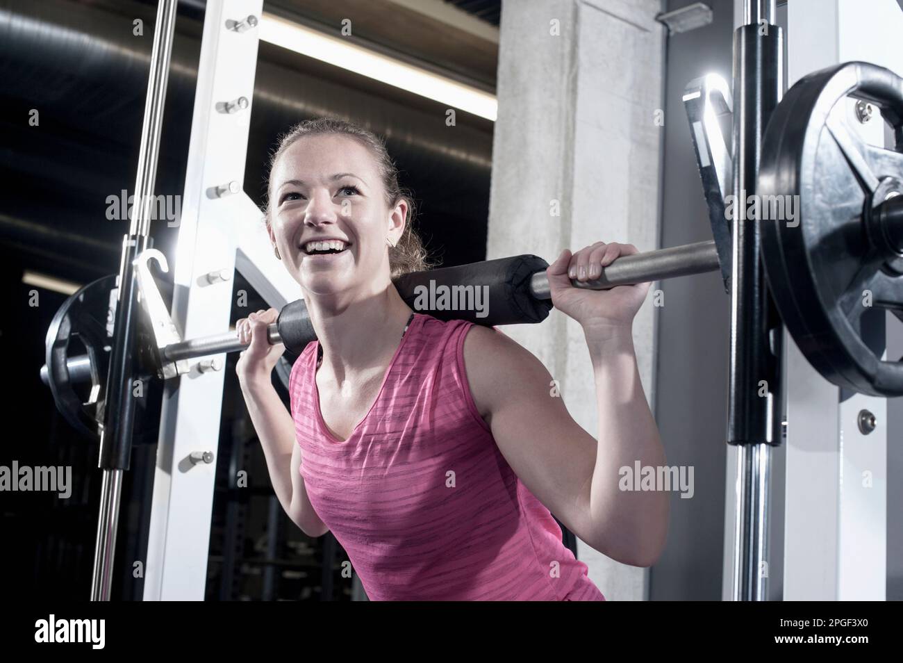 Mid adult woman doing squats barbell on her shoulders in the gym ...